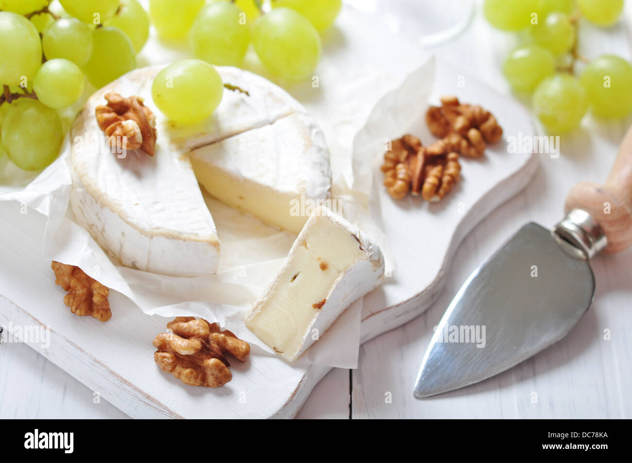 Camembert on wooden cutting board with grape and walnut closeup Stock ...