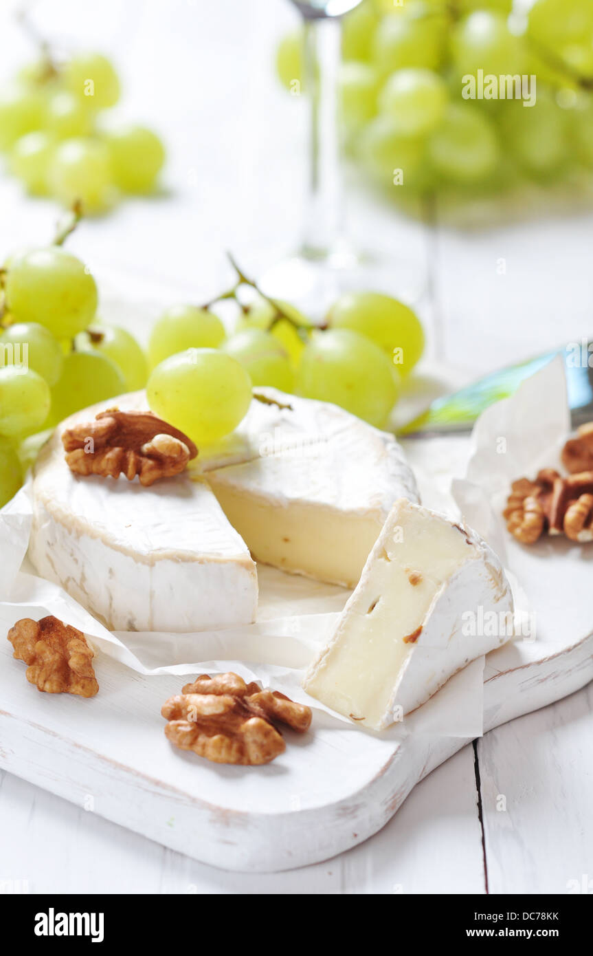Camembert on wooden cutting board with grape and walnut closeup Stock ...