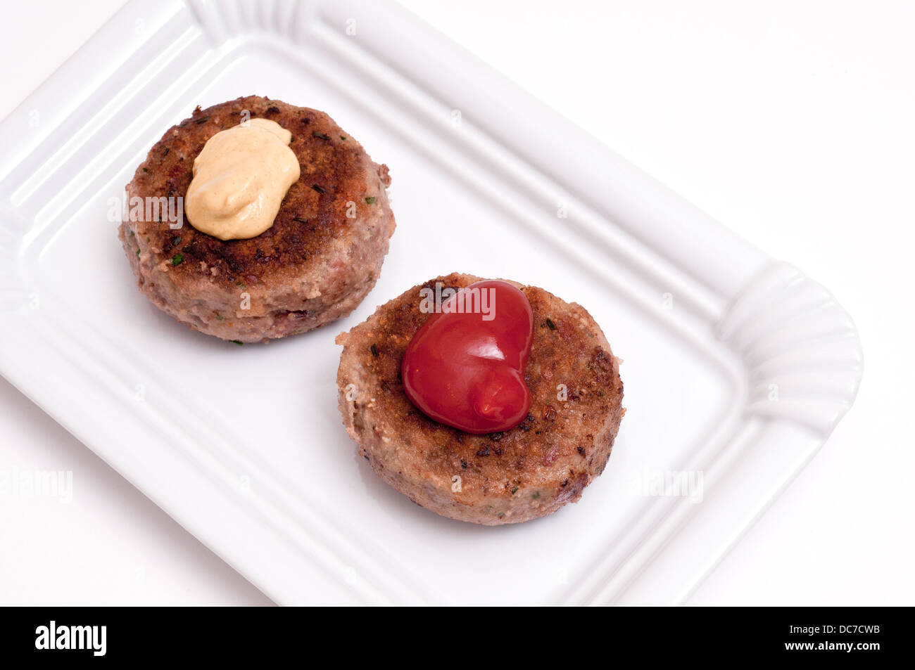 Two meatballs on a plate with mustard and ketchup Stock Photo - Alamy