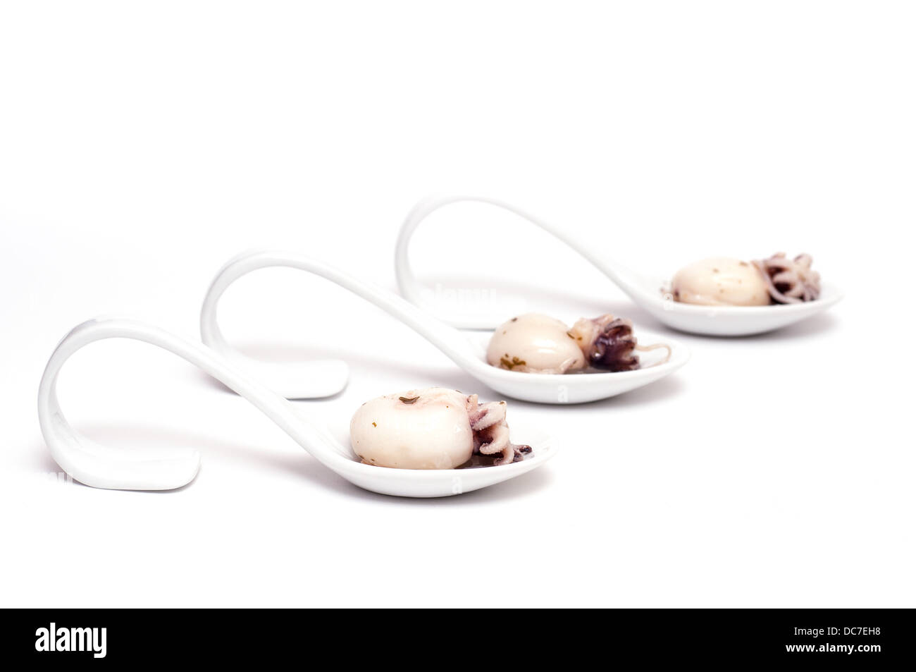 Three spoons with seafood of a squid Stock Photo - Alamy