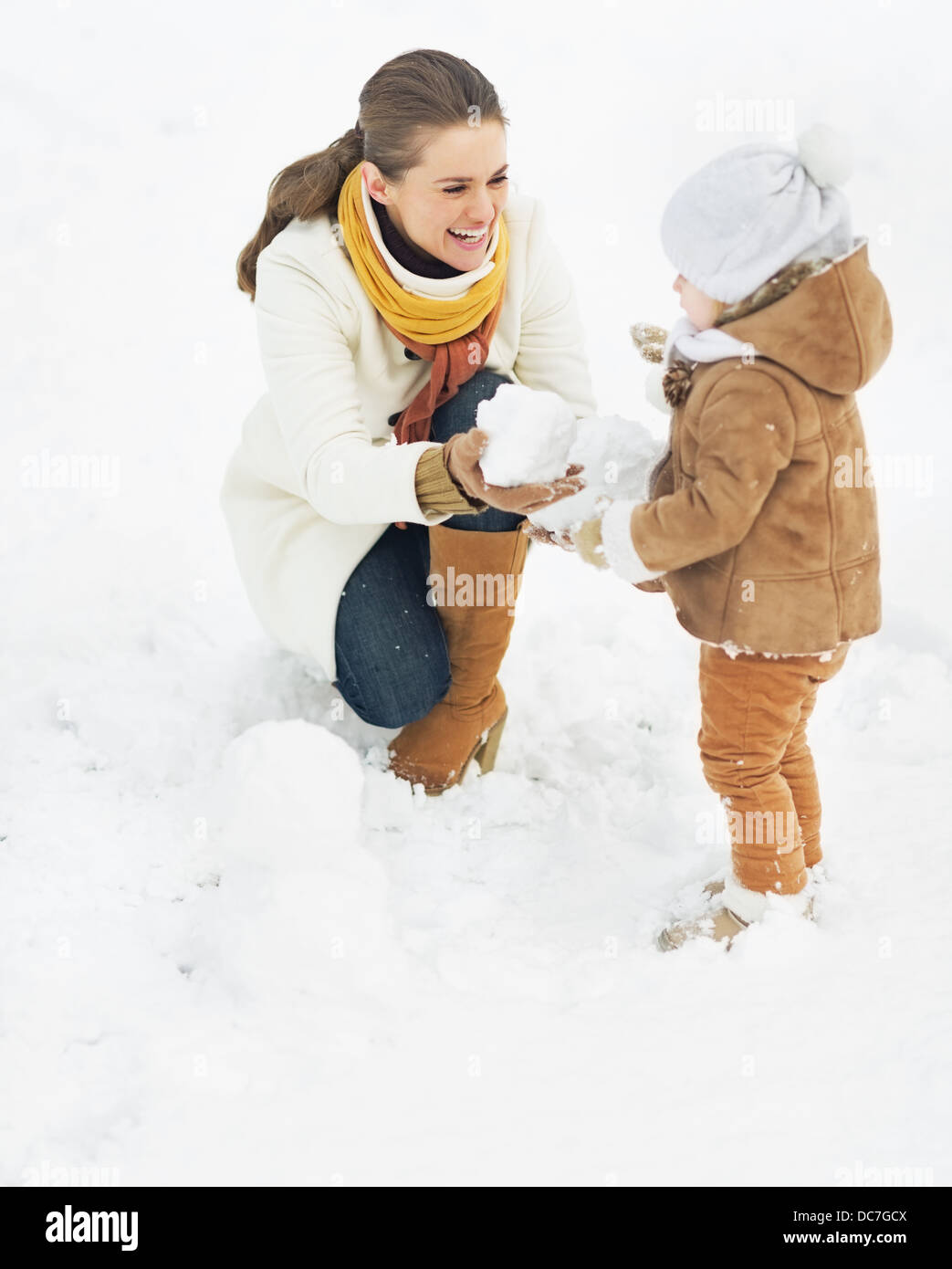Happy mother and baby making snowman in winter park Stock Photo - Alamy