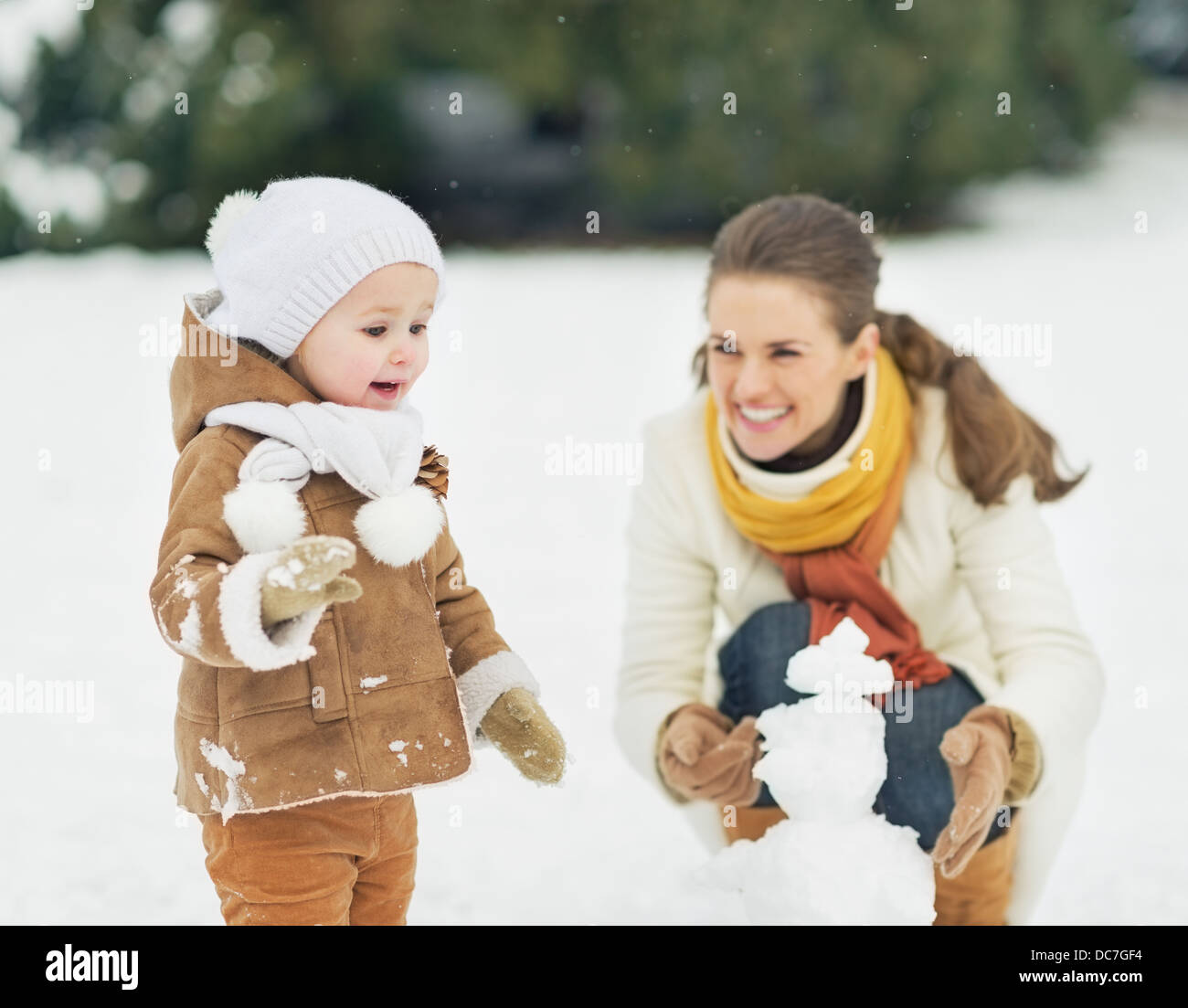 Happy mother and baby making snowman in winter park Stock Photo - Alamy