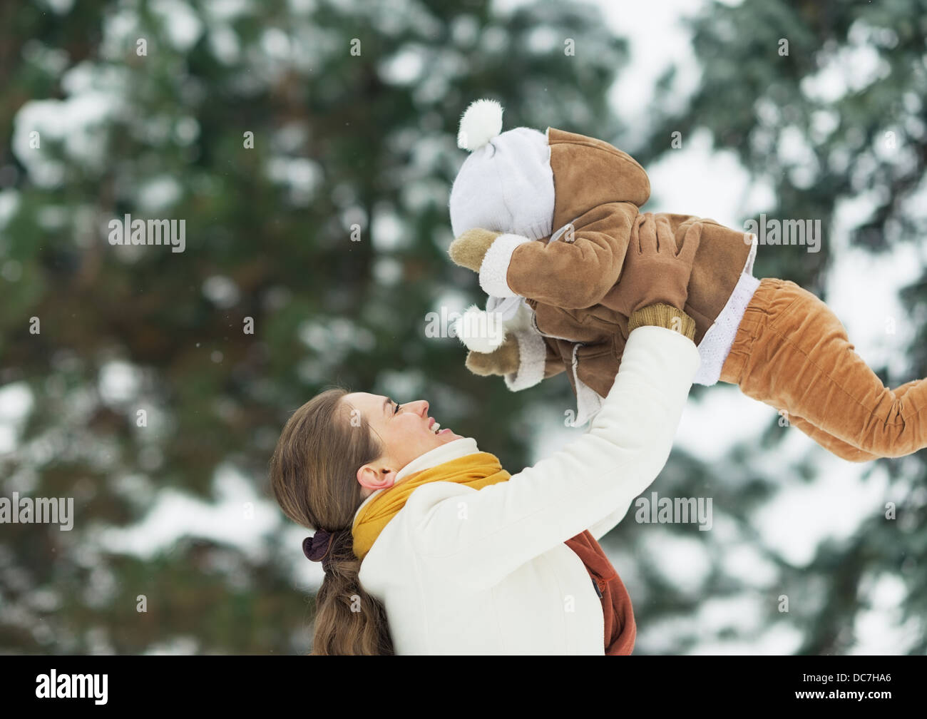 Happy mother throwing baby up in winter park Stock Photo - Alamy