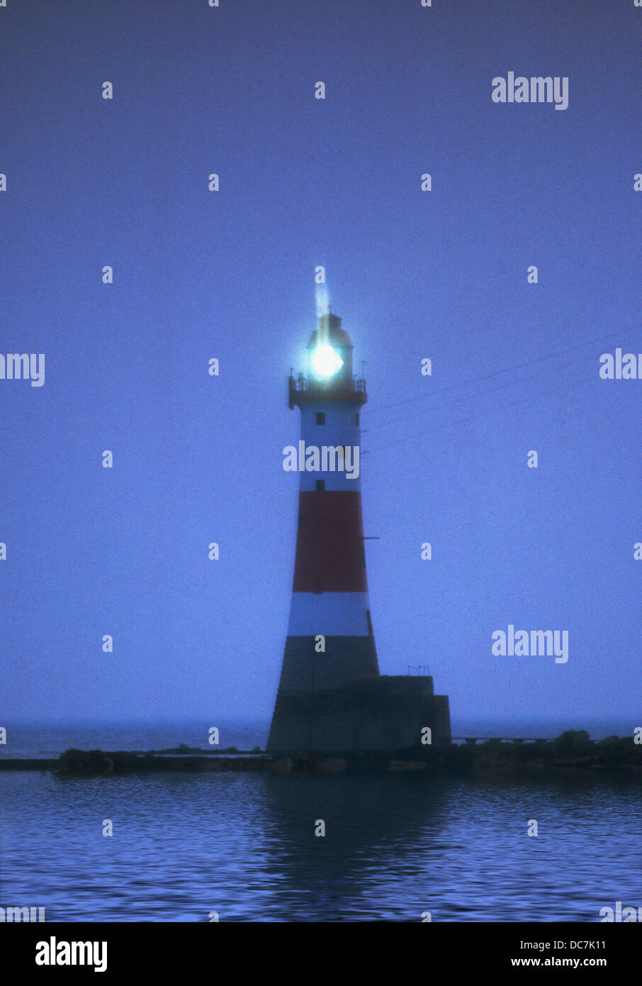 Lighthouse with light beam at dusk and high tide Stock Photo - Alamy