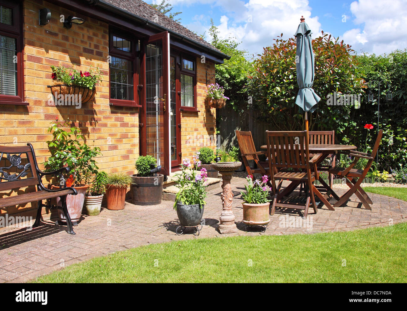 An English Back garden scene with patio, seating area and flowerpots ...
