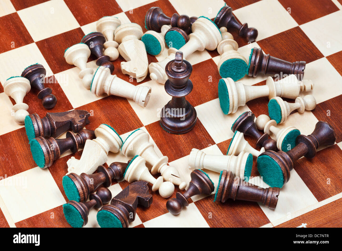 lonely black king and scattered chess pieces on chessboard Stock Photo ...