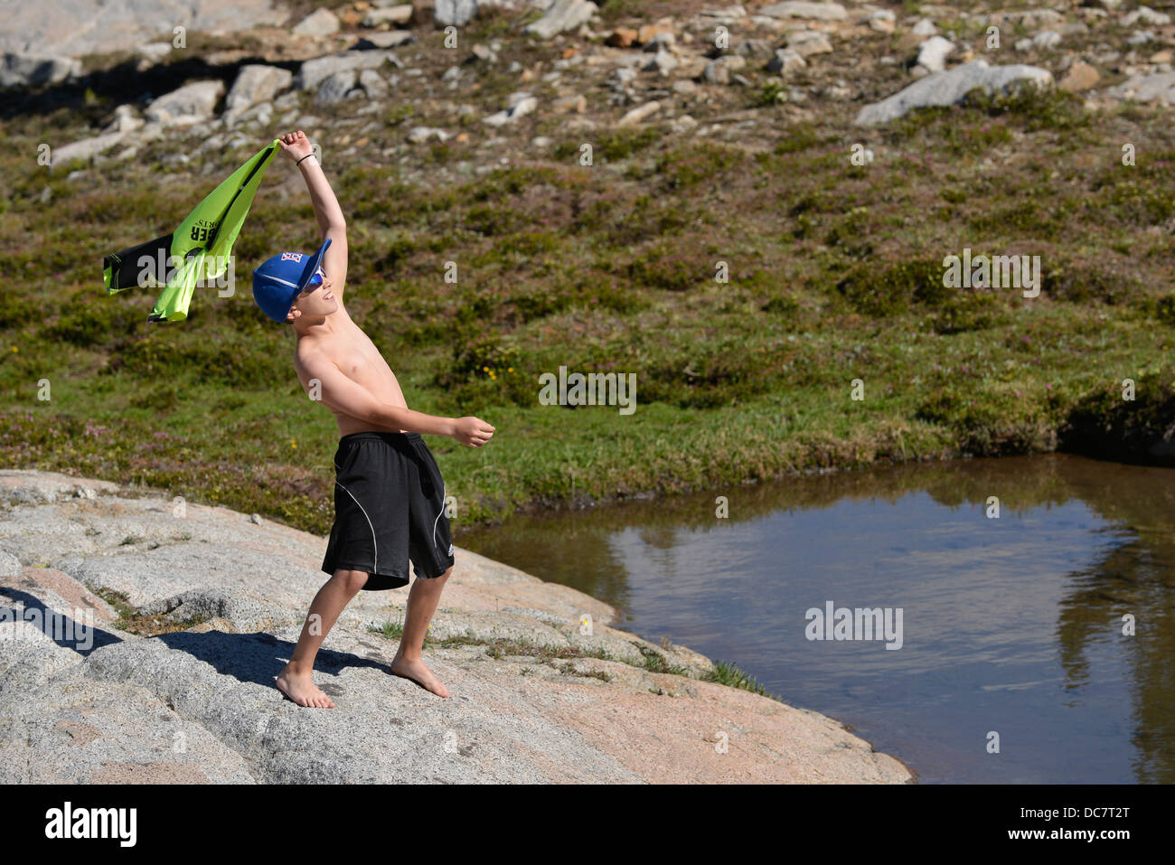 Boy twirling his shirt by a pond high in the Wallowa Mountains of ...