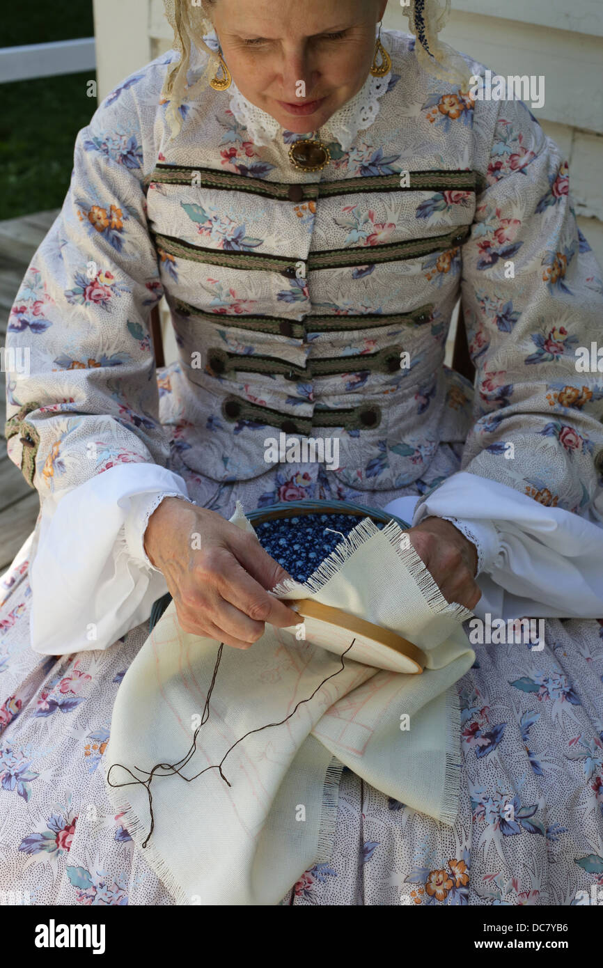 A woman dressed in pioneer clothing and doing needle work Stock Photo ...