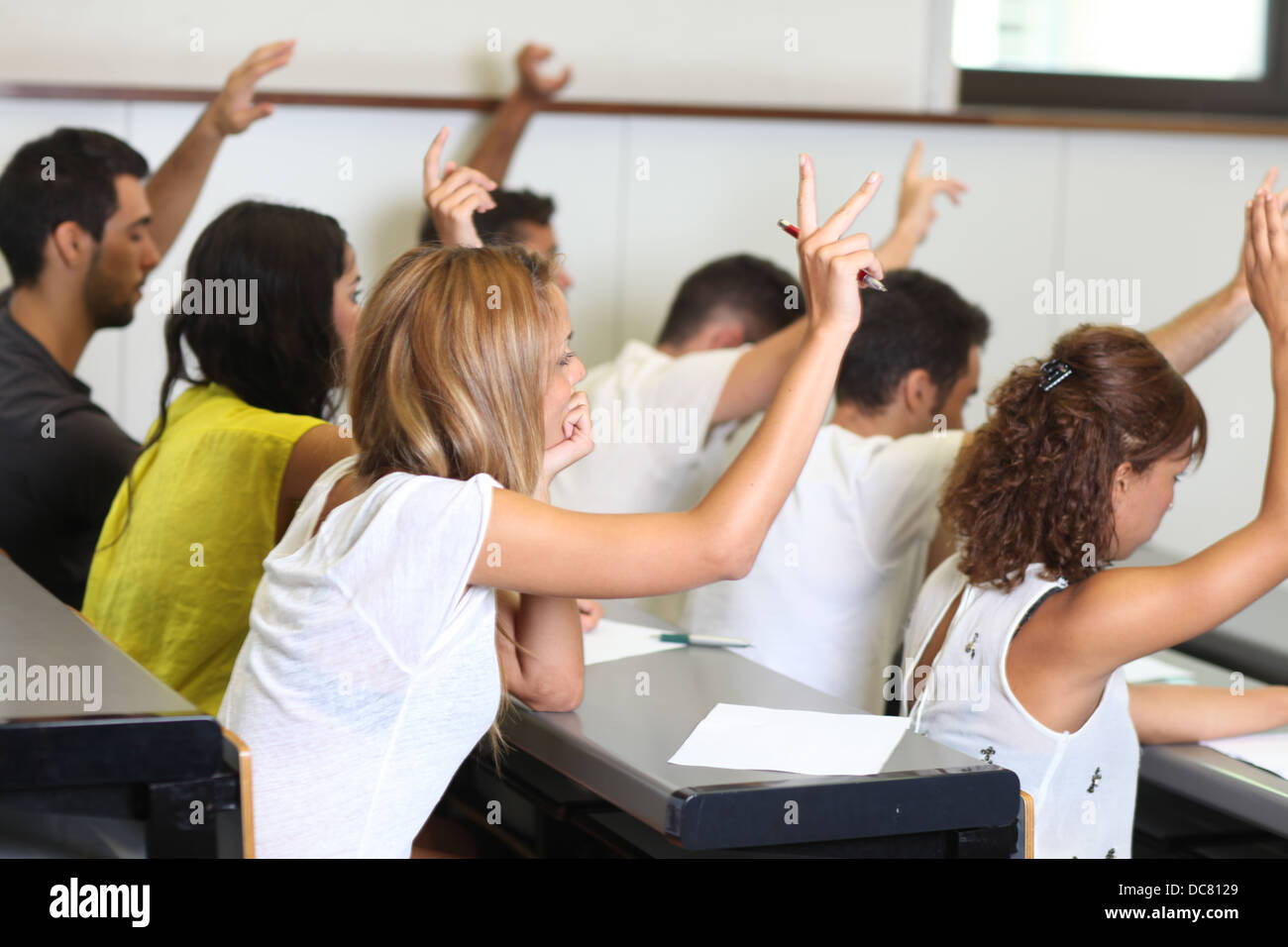 pupils put hand up in classroom Stock Photo - Alamy