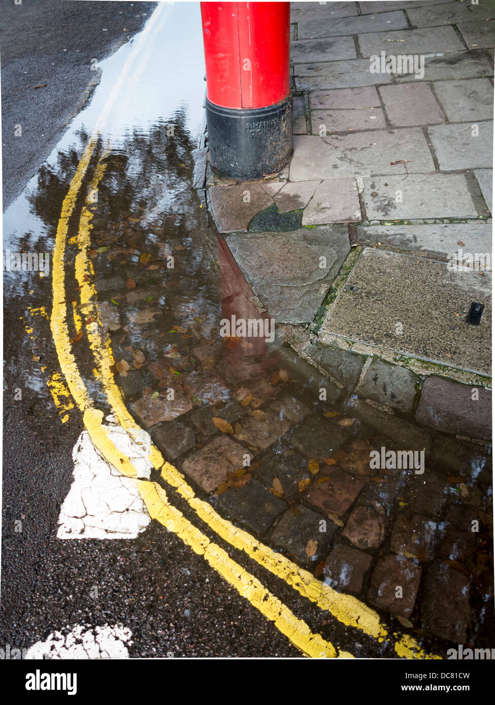Large puddle in gutter of road, with red post box Stock Photo - Alamy