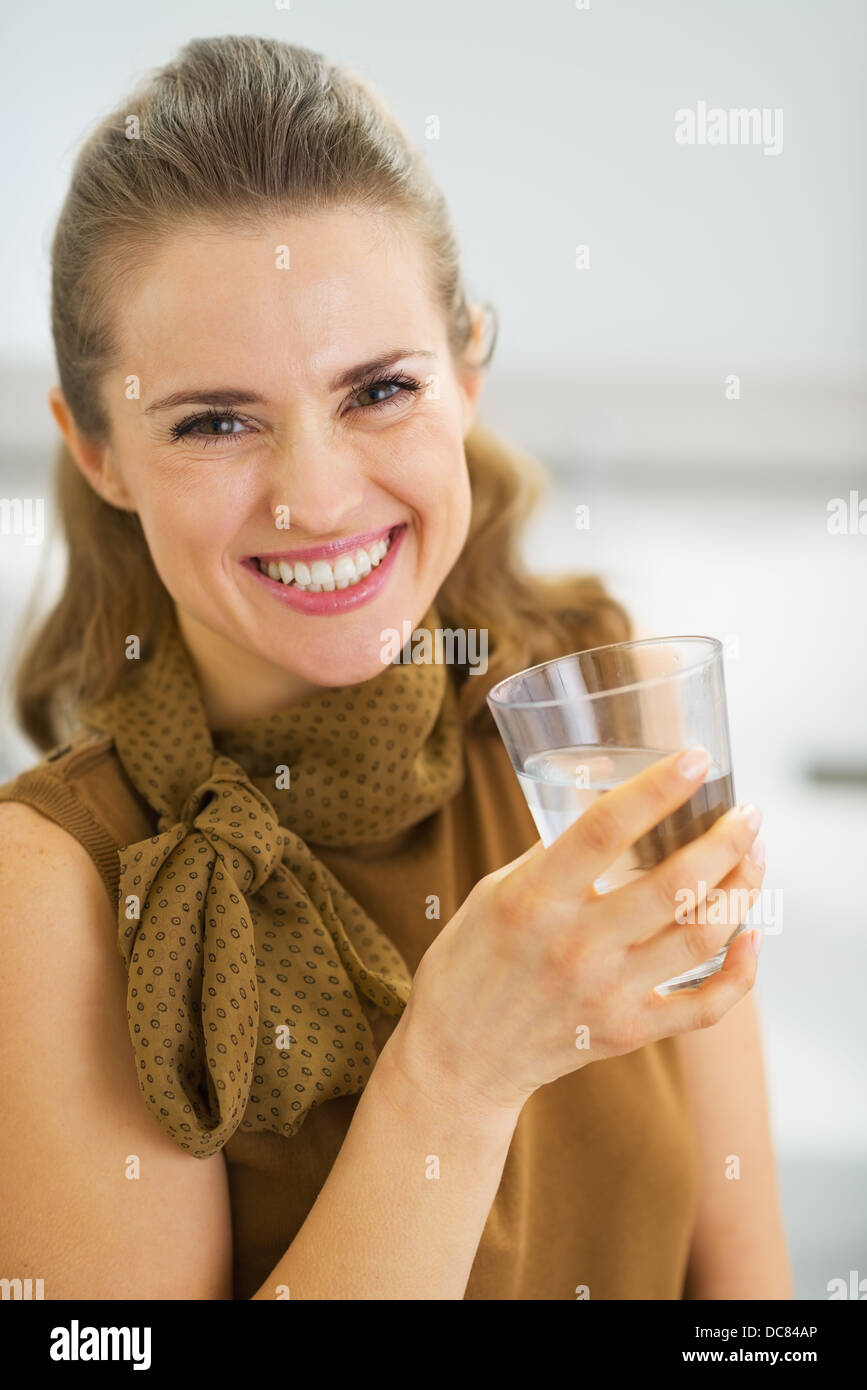 Portrait of smiling young woman drinking water in kitchen Stock Photo - Alamy