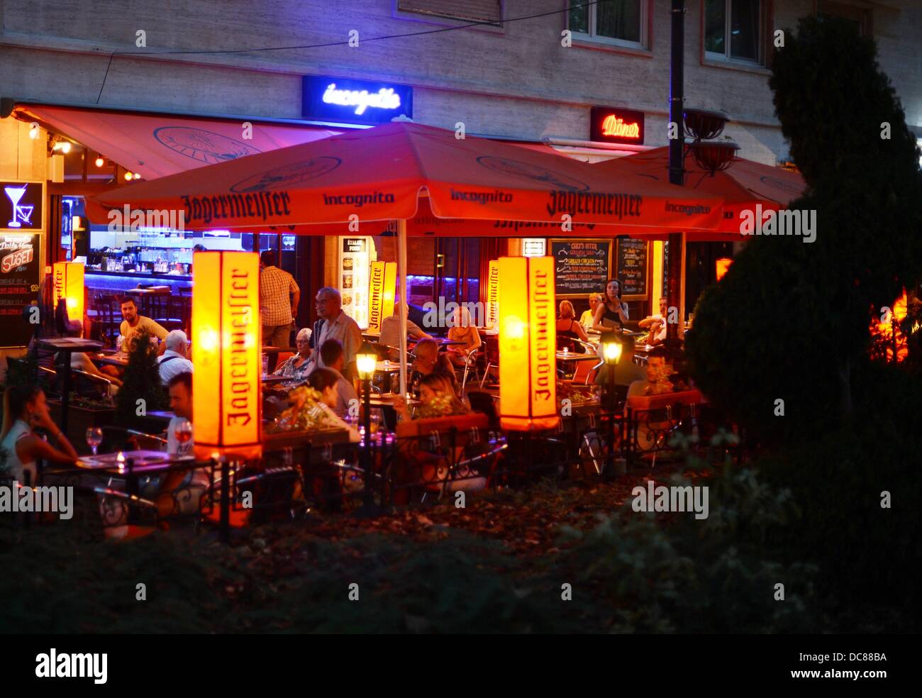 People sit in the illuminated Incognito Bar Cafea at the Liszt Ferenc ...