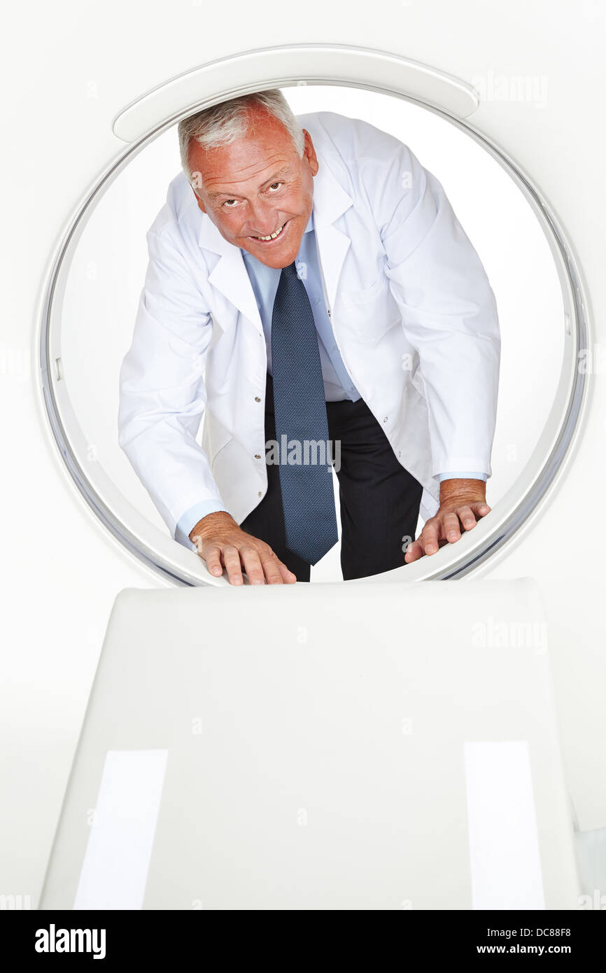 Smaling senior doctor looking through MRI scan tube Stock Photo - Alamy
