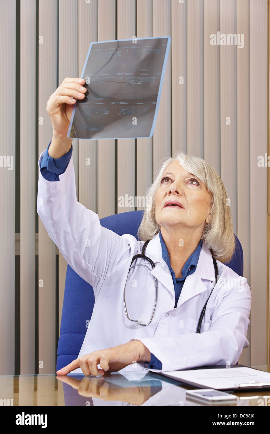 Doctor looking at x-ray image at desk in office Stock Photo - Alamy