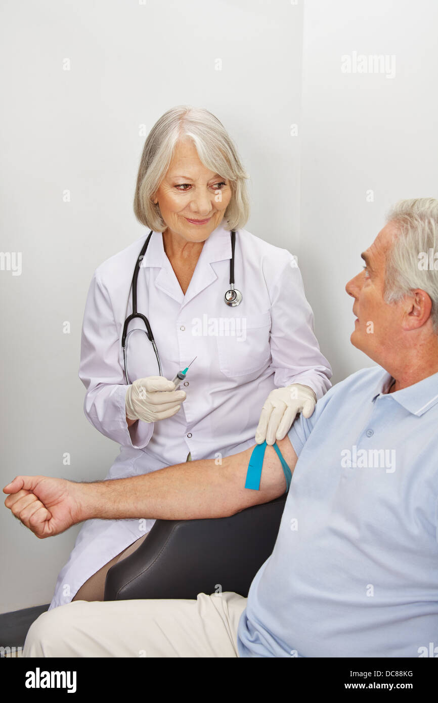 Doctor withdrawing blood from senior patient with a syringe in a ...