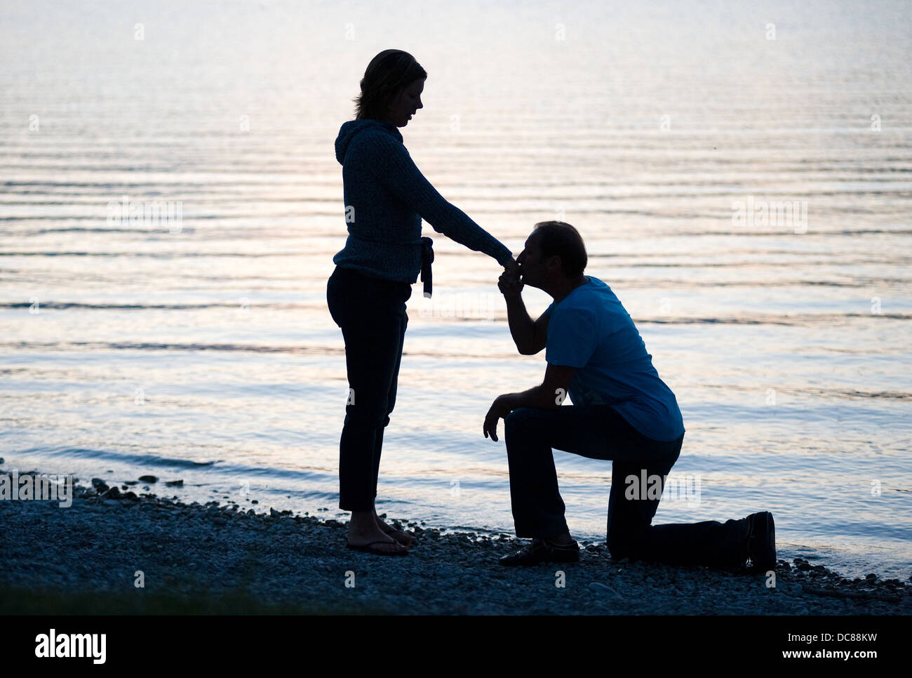 A man is kissing the hand of his girlfriend on his knee Stock Photo - Alamy