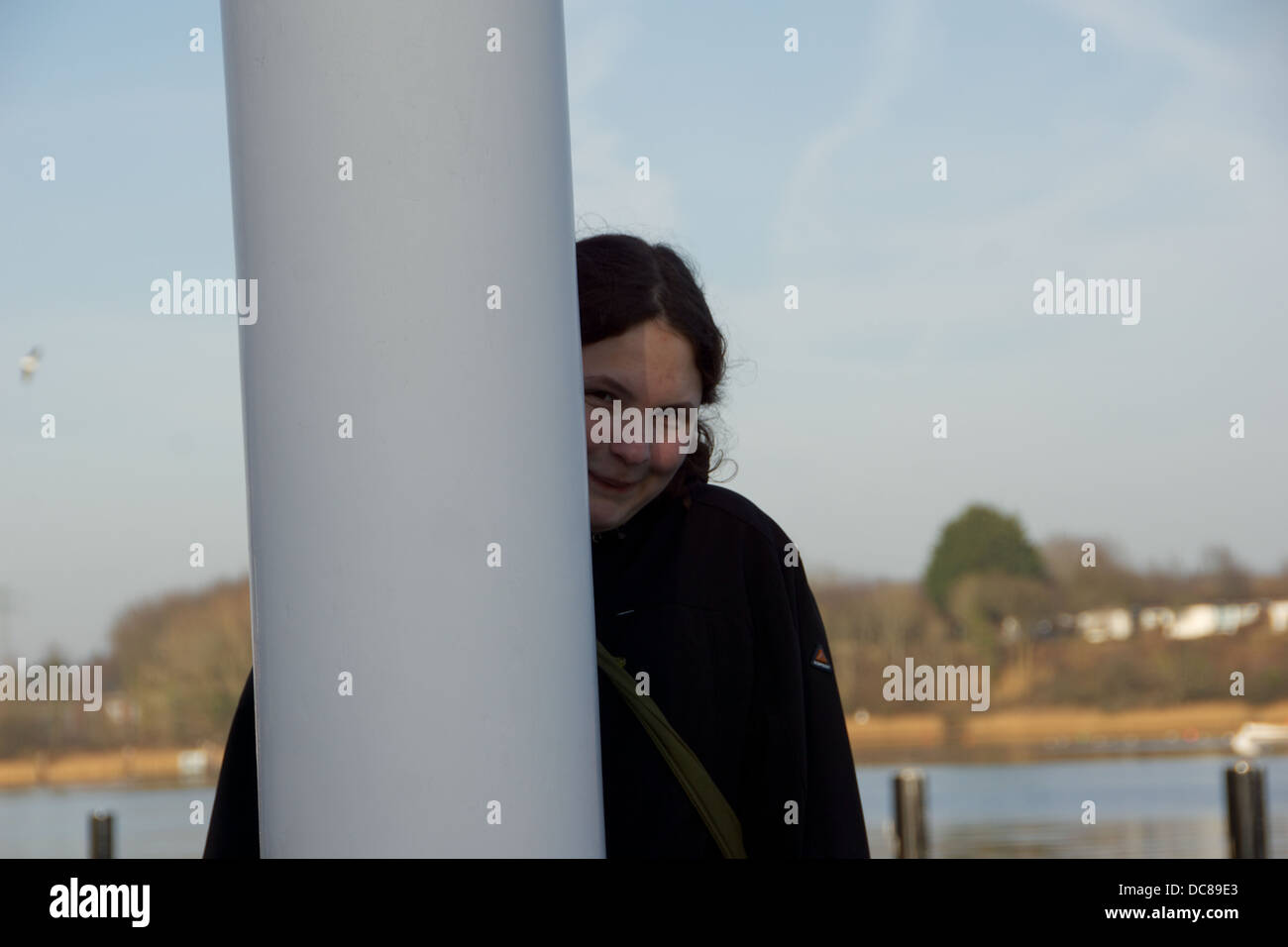 Young woman is hiding behind a pole Stock Photo - Alamy