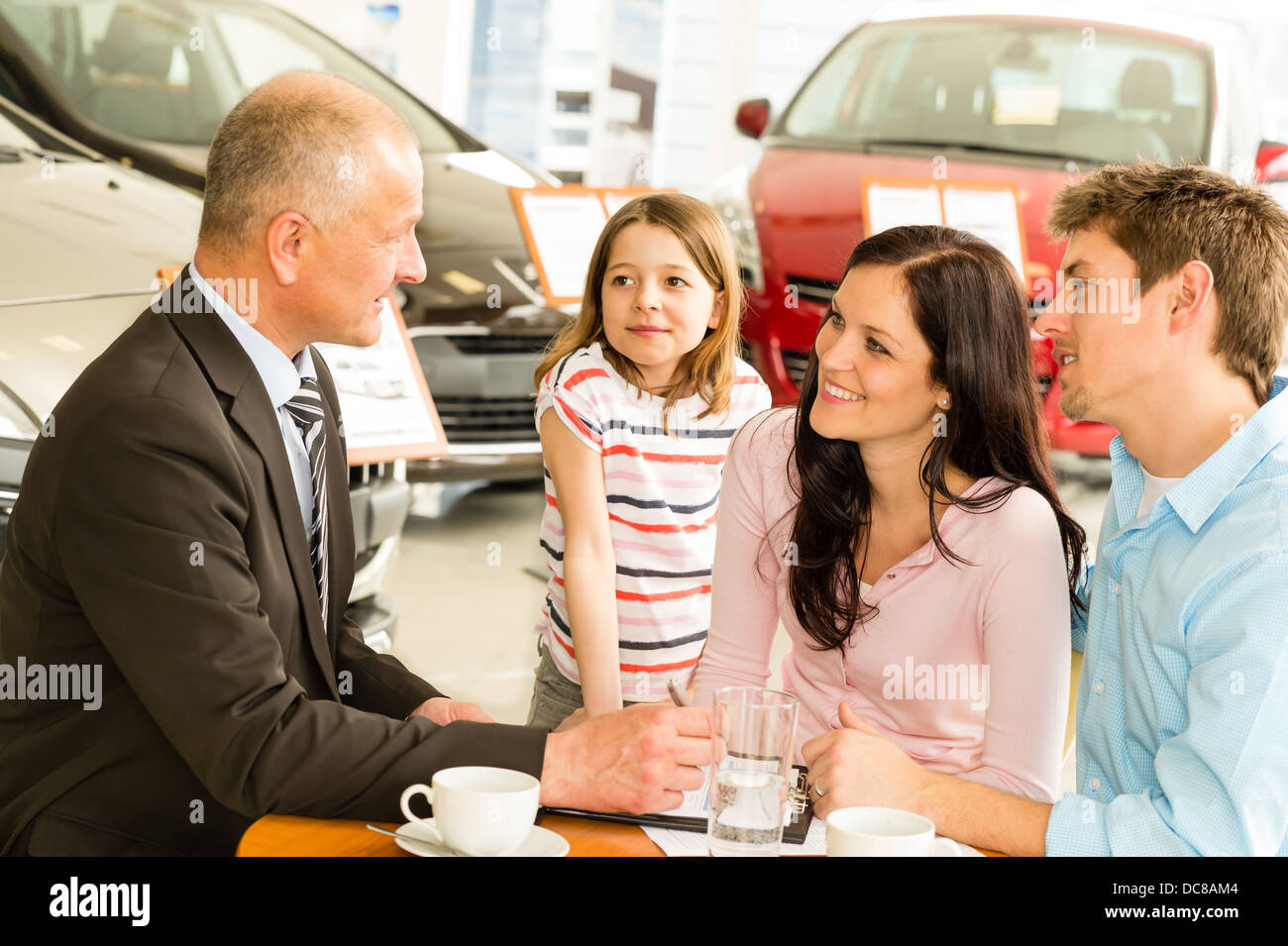 Car salesman and caucasian couple doing paperwork Stock Photo - Alamy
