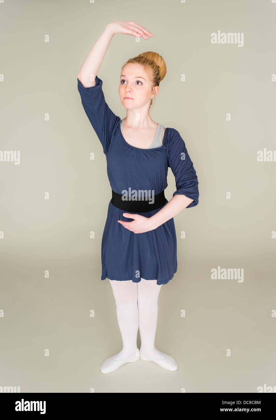 Young blond female teenager in ballet dress standing in dance pose ...