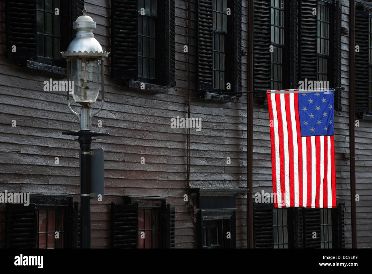 A 15 star flag flying in front of a colonial era house in the ...