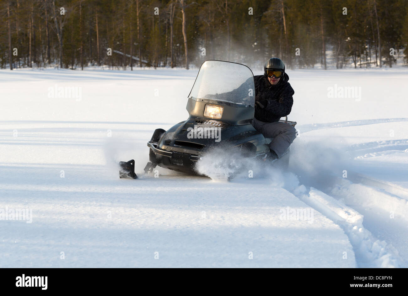 man riding a snowmobile on a background of forest Stock Photo - Alamy