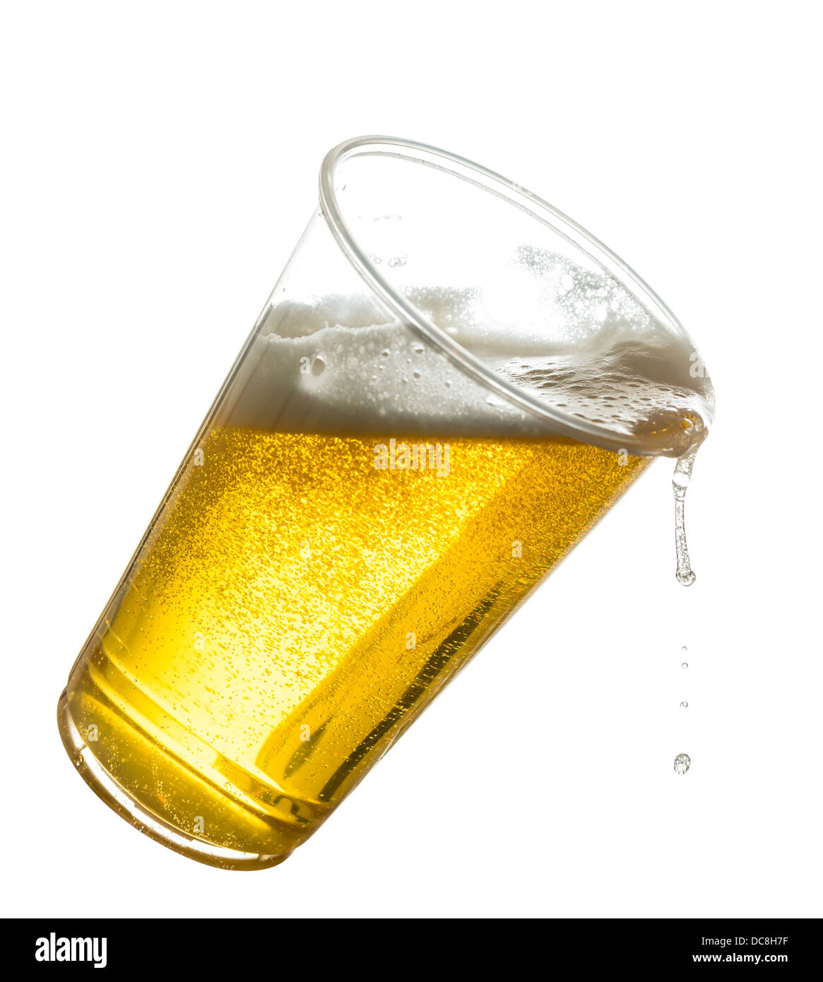 Beer / lager in a tilting plastic disposable pint glass spilling over ...