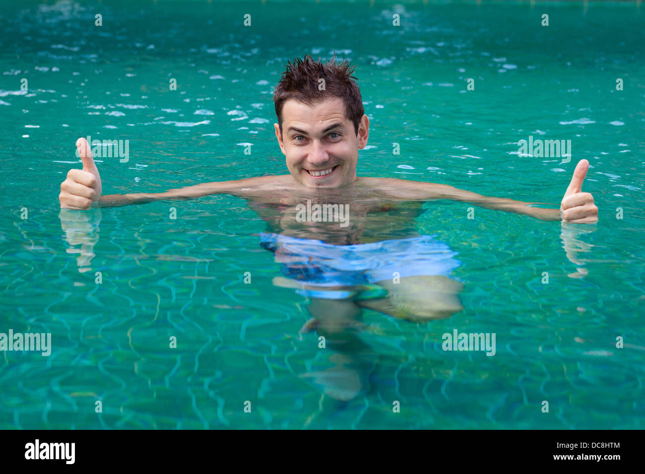 Young happy man in the swimming pool gesturing thumb up Stock Photo - Alamy