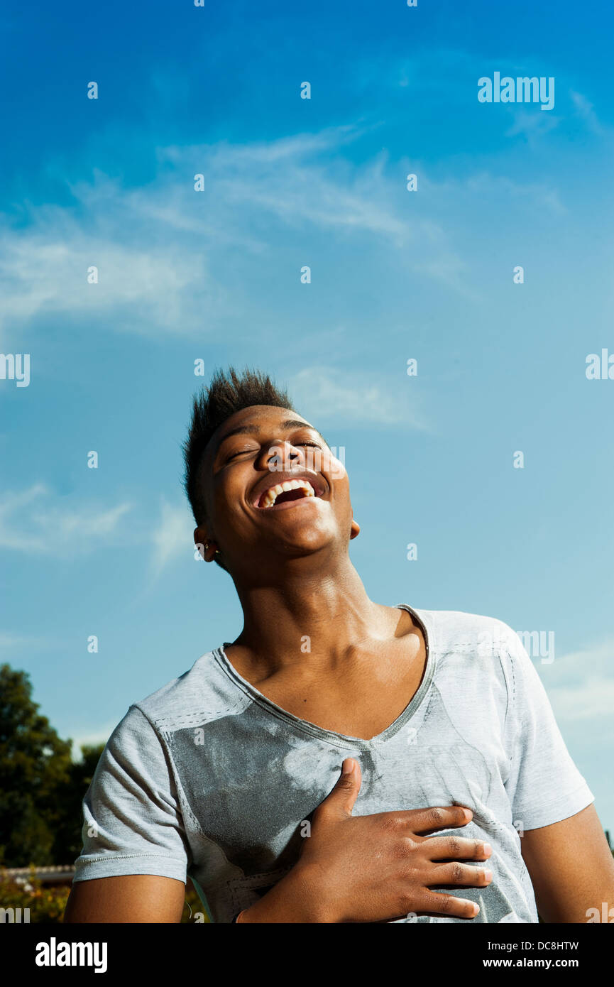 Young man laughing in front of a blue skyline Stock Photo - Alamy