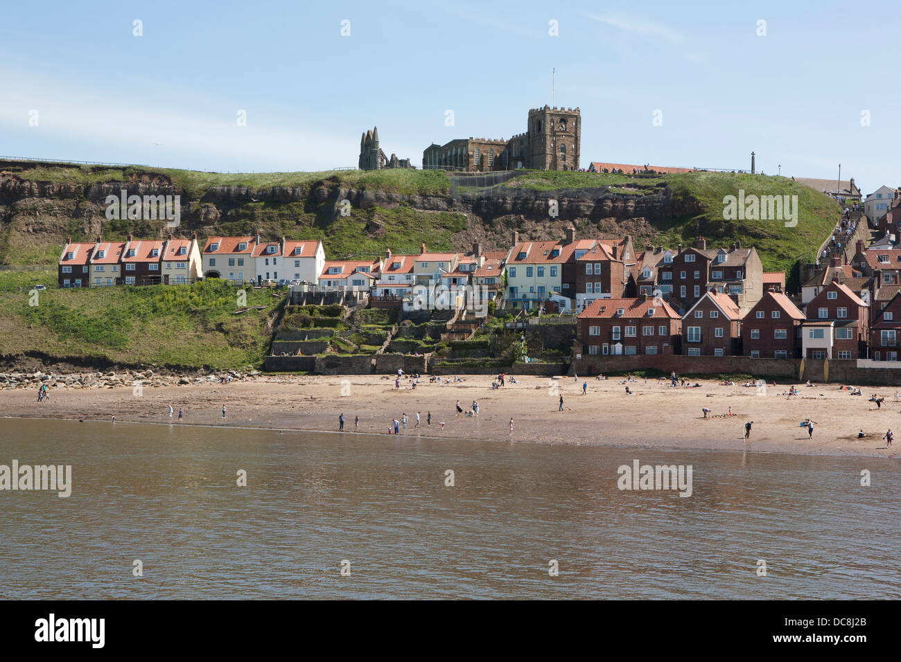 People enjoying the beach at Whitby, the harbor houses and the abbey ...