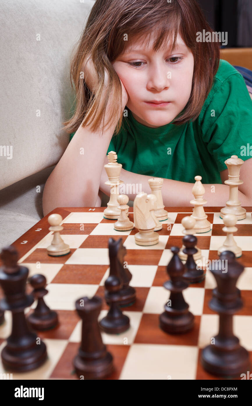 little girl thinking over chess game lying on couch Stock Photo - Alamy