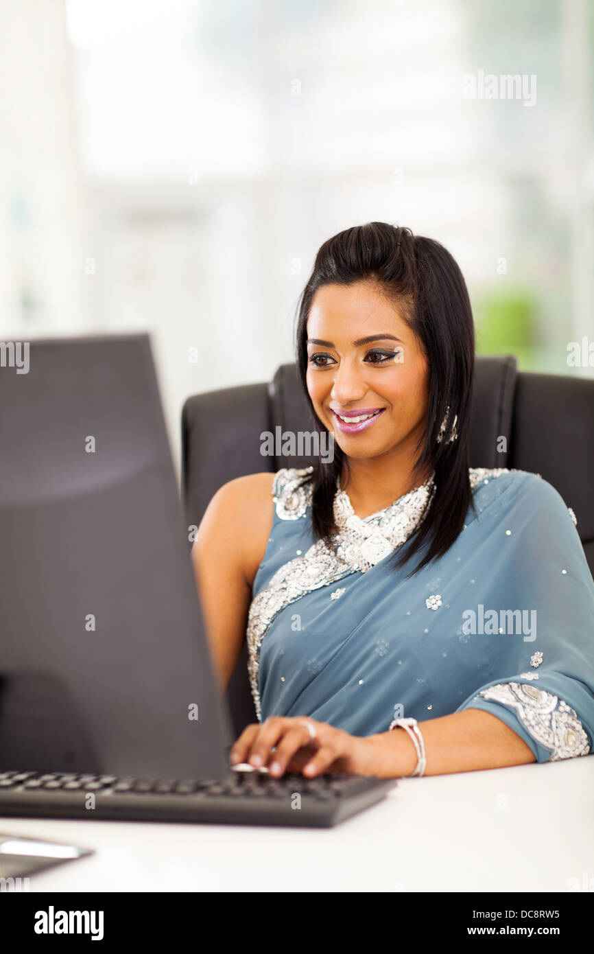 happy Indian woman in traditional clothing using computer at work Stock ...