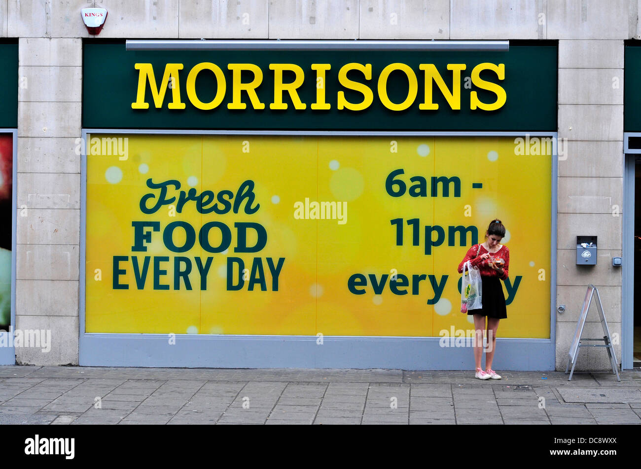 A woman stands outside Morrisons local in central London, UK Stock ...