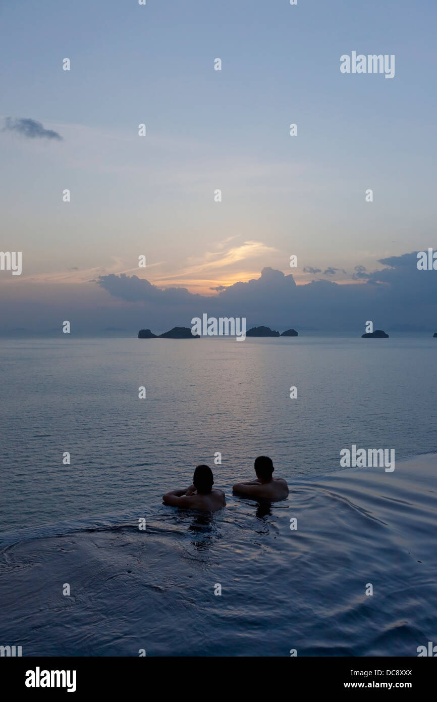 Two people at the edge of an infinity pool enjoying the sunset; Ko ...
