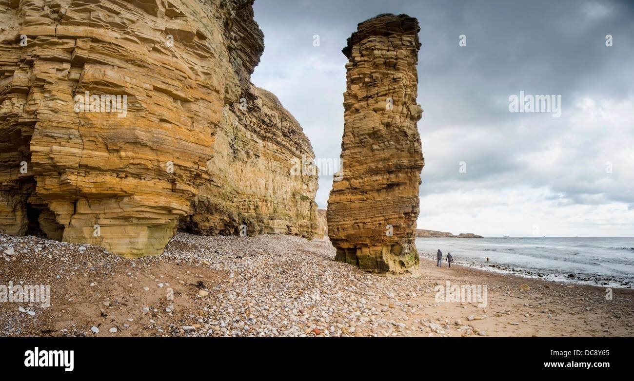 Walking on the beach beside large rock formations; South Shields, Tyne ...