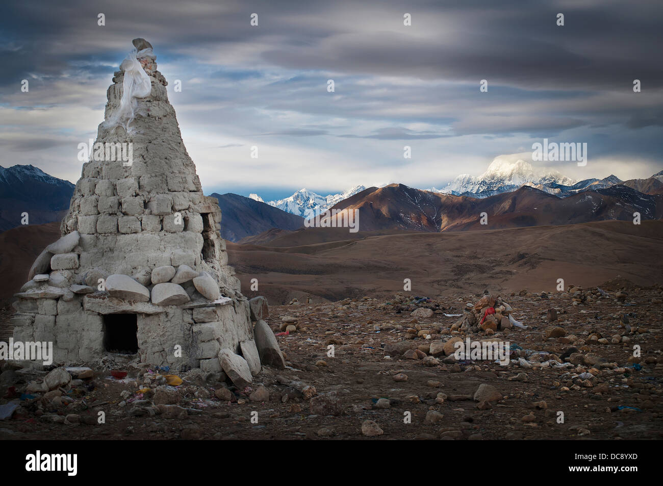 A stone conical structure on a barren landscape with mountains in the ...