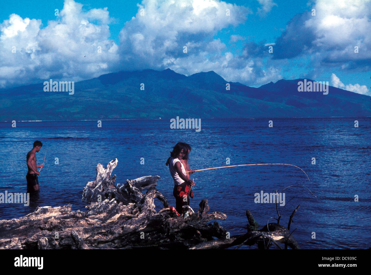 Woman fishing on the island of Moorea with Tahiti in background, 1968 ...