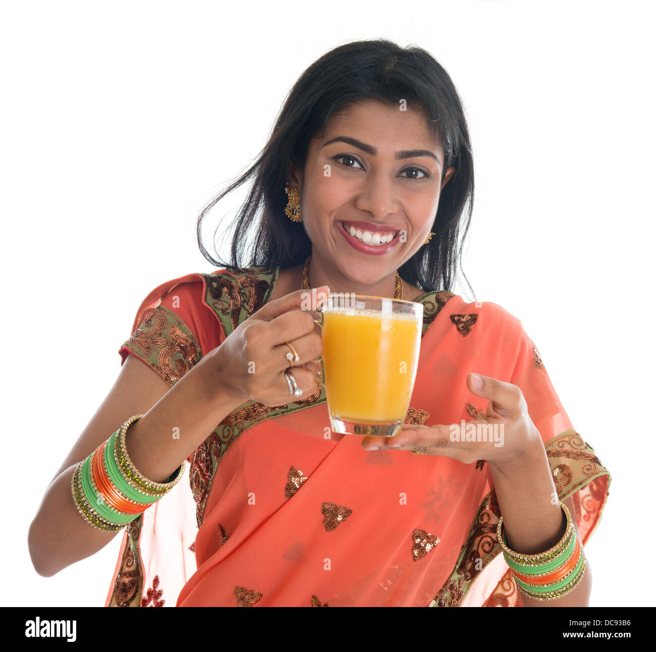 Happy traditional Indian woman in sari drinking a glass of orange juice ...