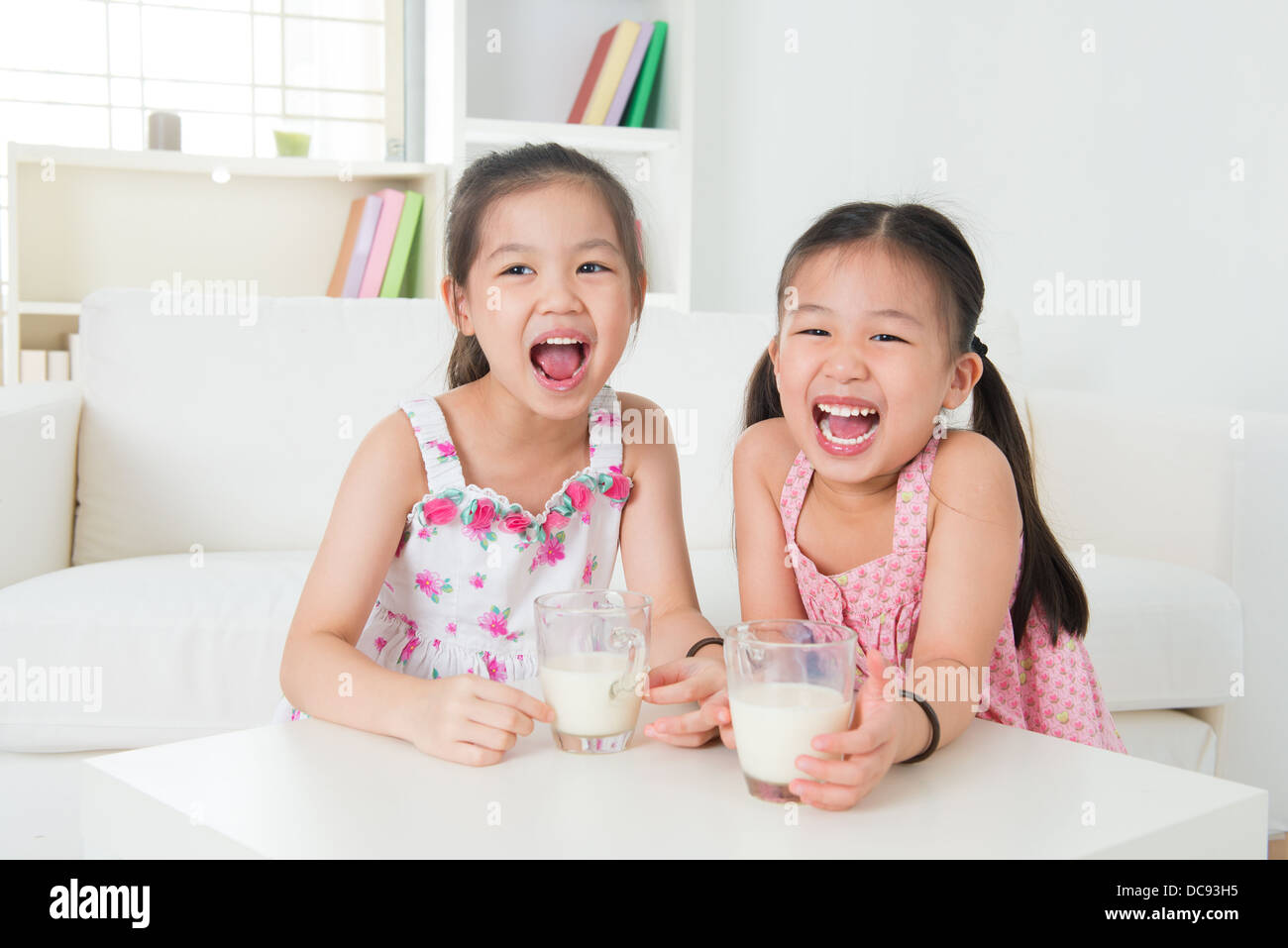 Children drinking milk. Asian family at home. Beautiful sister drinks ...