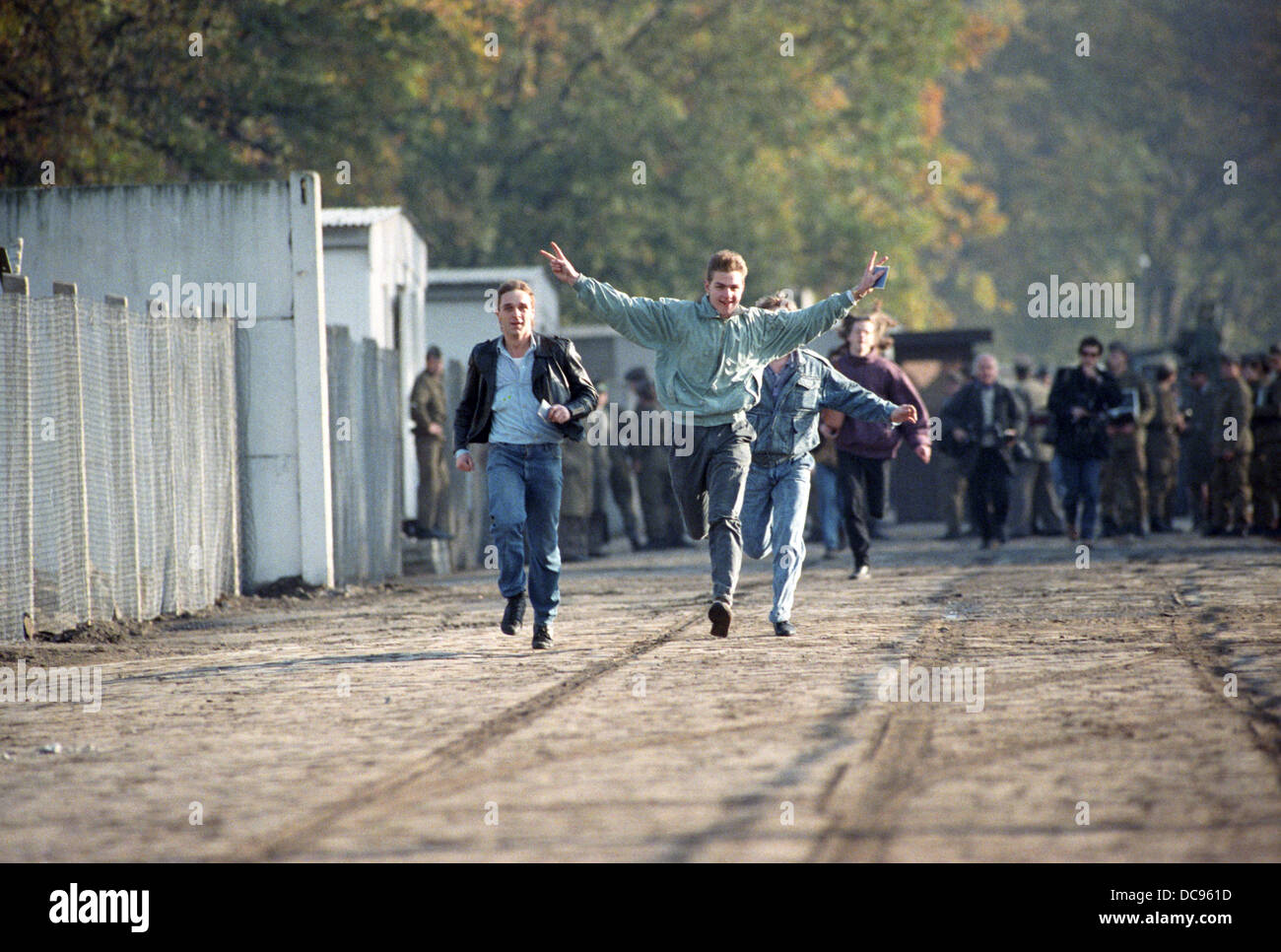 Young men run cheering through a broder crossing station in Berlin ...