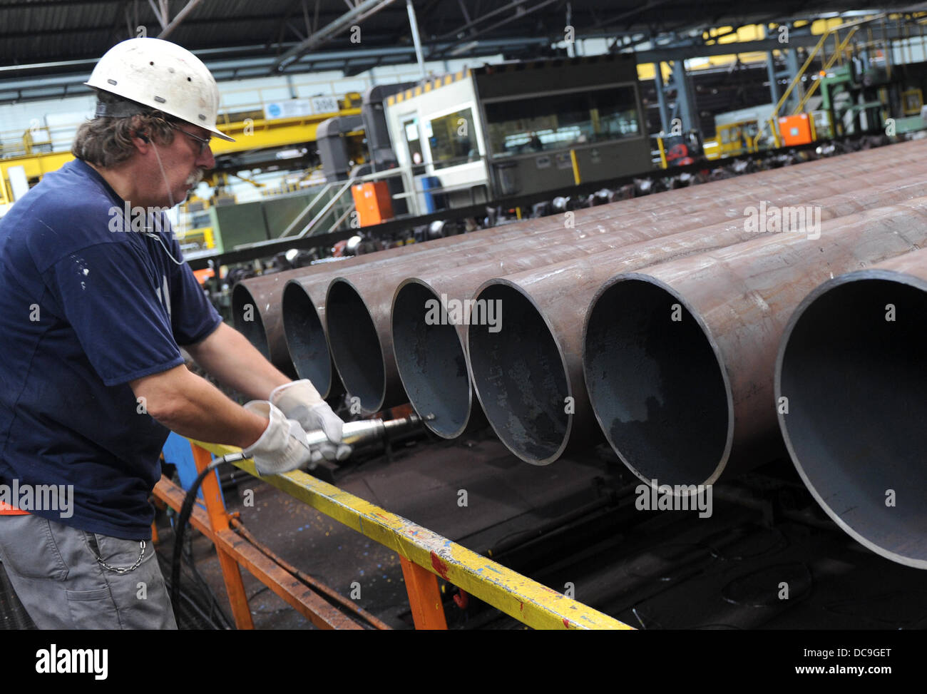 An employee checks a steel pipe in the manufacturing hall at Vallourec ...
