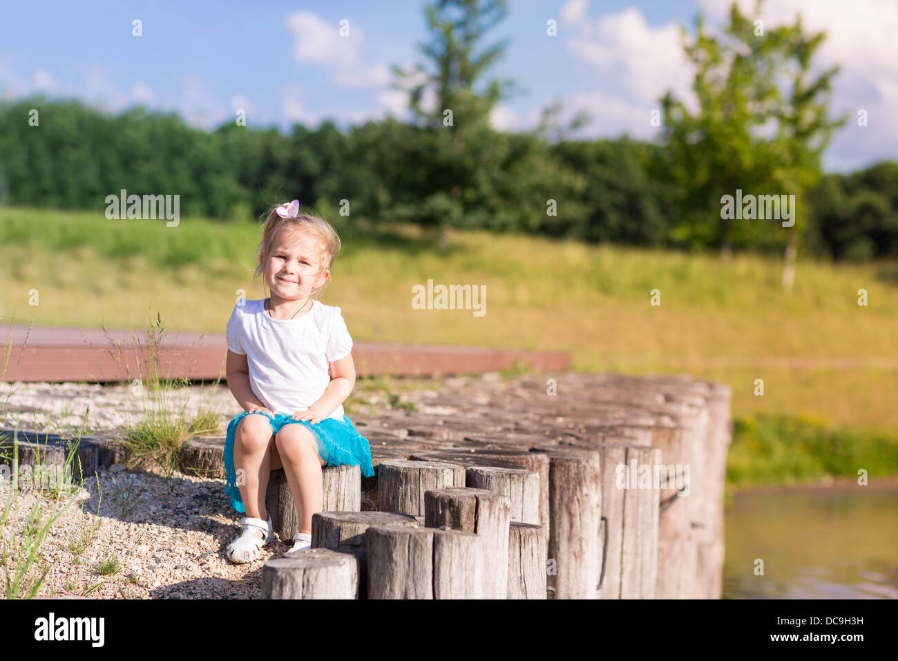 Cute little girl sitting near the lake in summertime in nature Stock ...