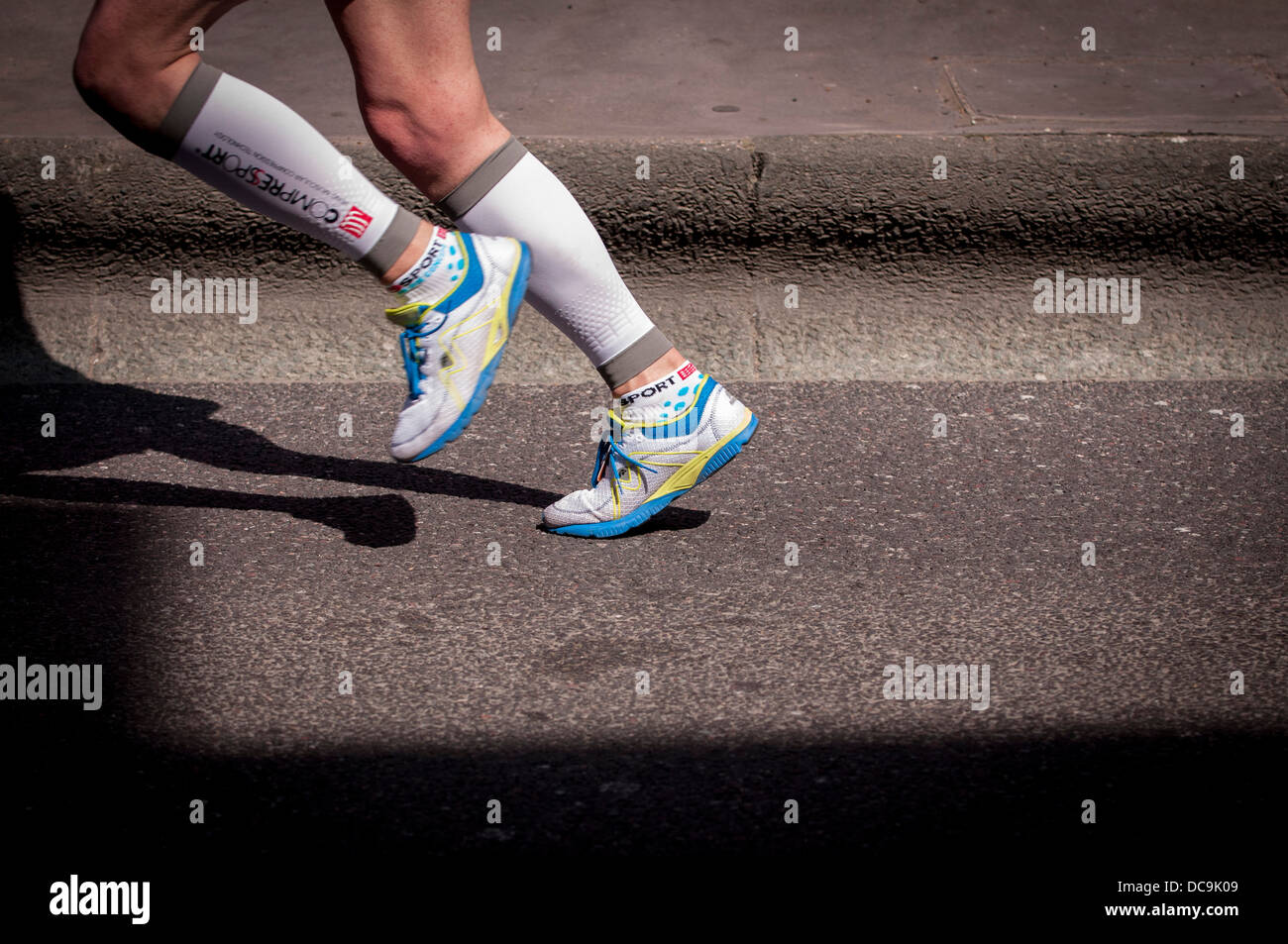 Athlete taking part in a race running by with shadow falling on to the ...