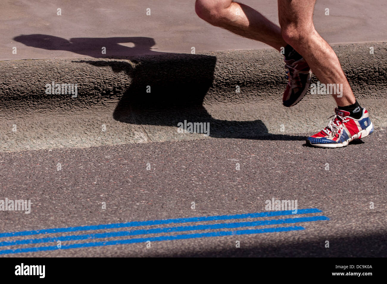 Athlete taking part in a race running by with shadow falling on to the ...