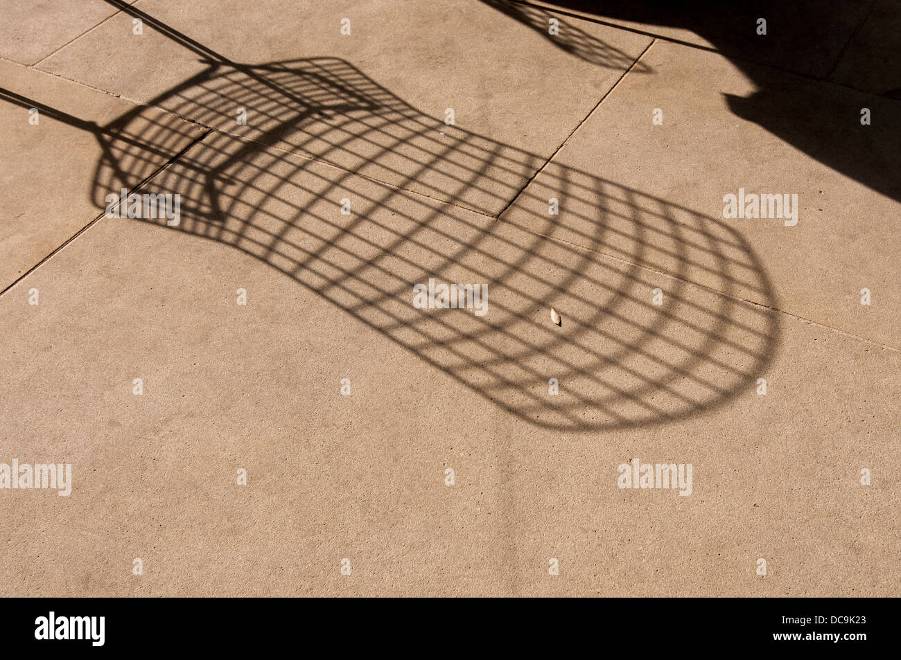 Shadow of the back of a metal chair on the pavement Stock Photo - Alamy