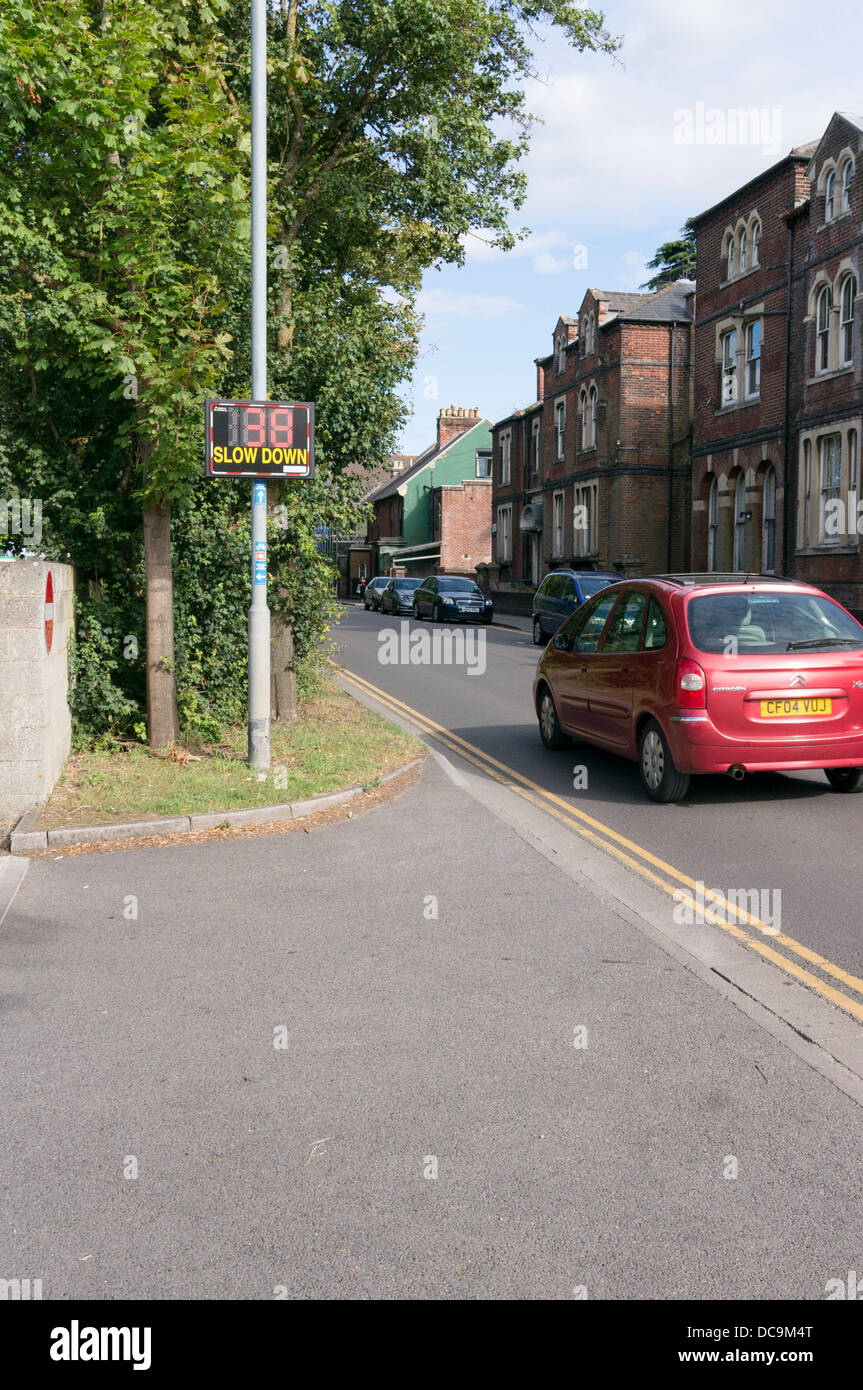 Car passing UK digital slow down traffic calming sign on side of road ...
