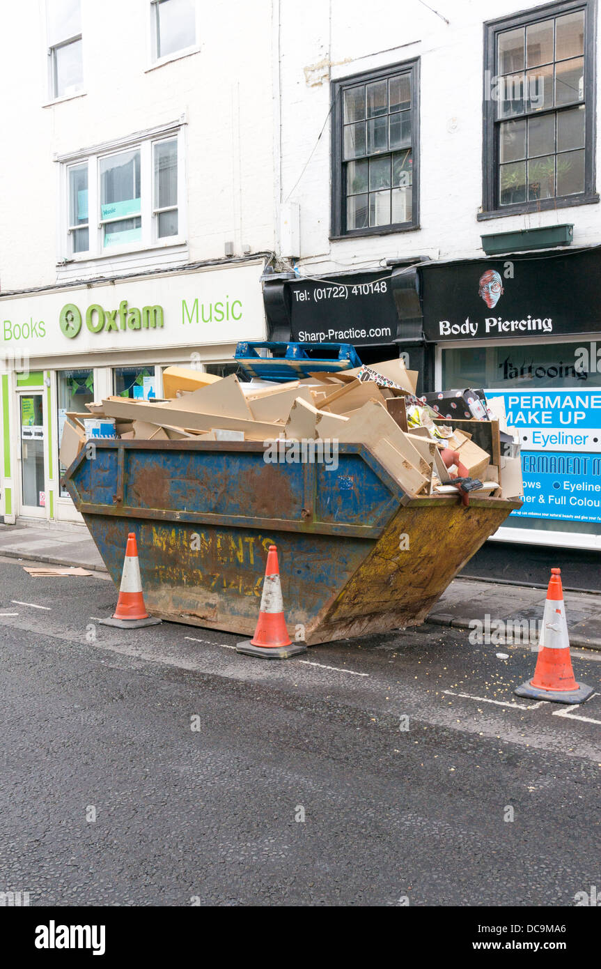 Full skip UK public high street road Stock Photo - Alamy