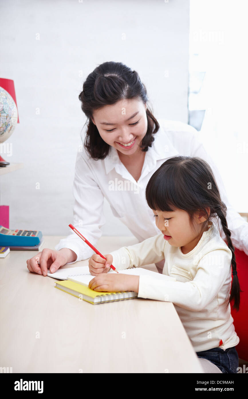 a kid studying at table with a teacher Stock Photo - Alamy