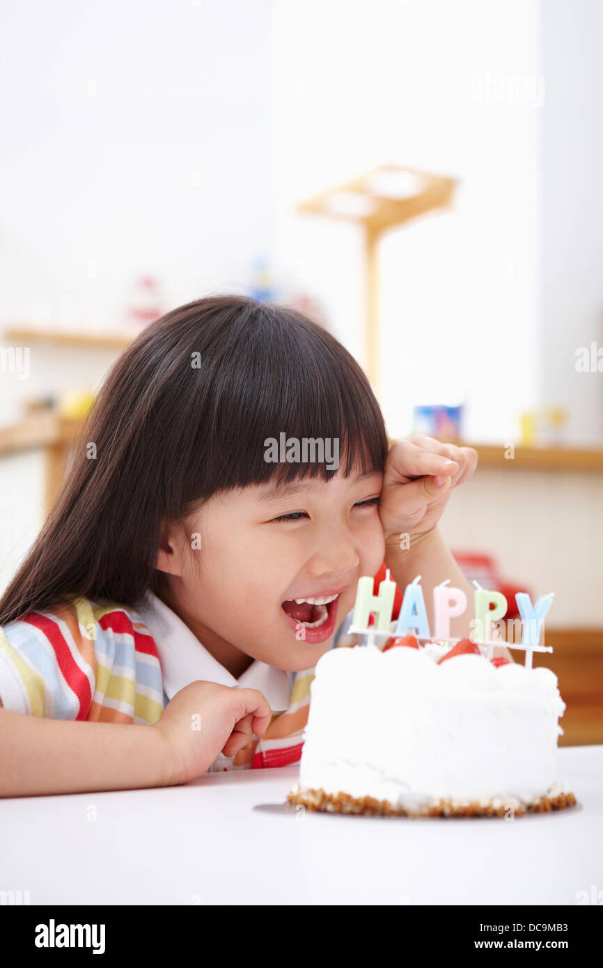 a kid with a birthday cake in front Stock Photo - Alamy