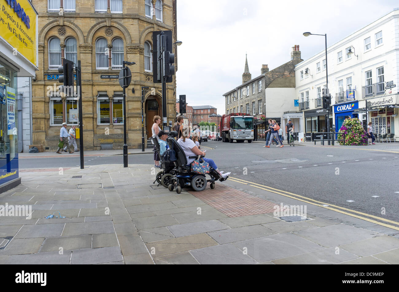 Disabled people in electric powered wheelchairs waiting to cross road ...