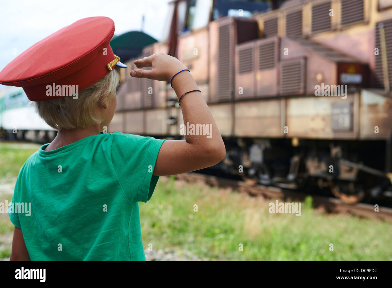 Child blond Boy with Train Dispatcher`s Cap playing in railway station ...